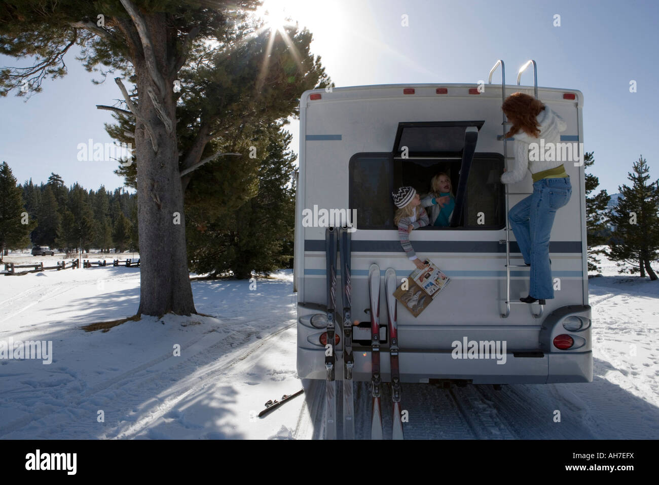 Mature woman climbing a ladder on a recreational vehicle with her two ...