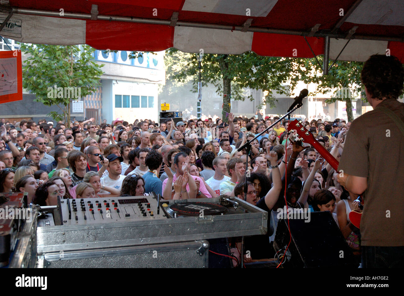 Crowd of young people dancing and cheering at street concert during ...