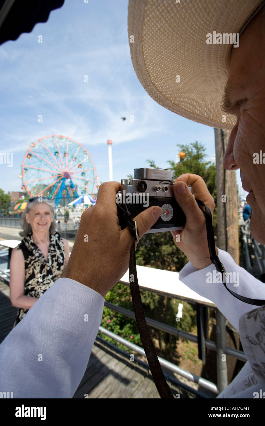 Senior man photographing a senior woman, The Wonder Wheel, Coney Island ...