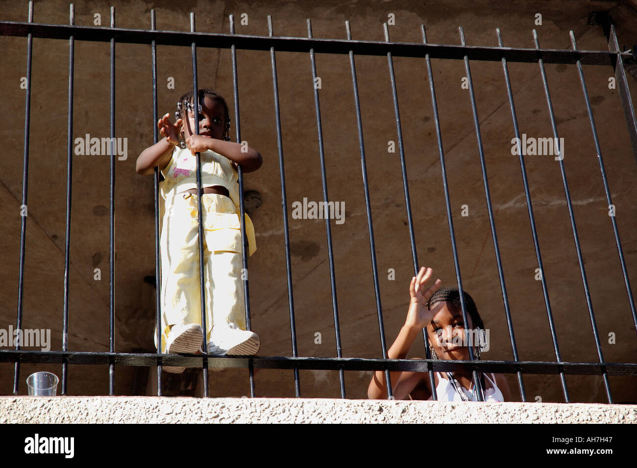 Small child hanging onto railings from balcony of upper floor of ...