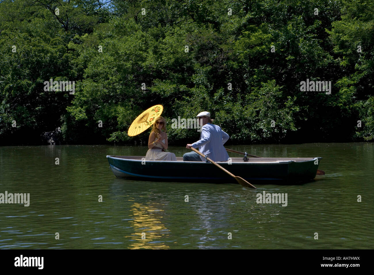 Young man rowing a boat with a young woman sitting in front of him ...