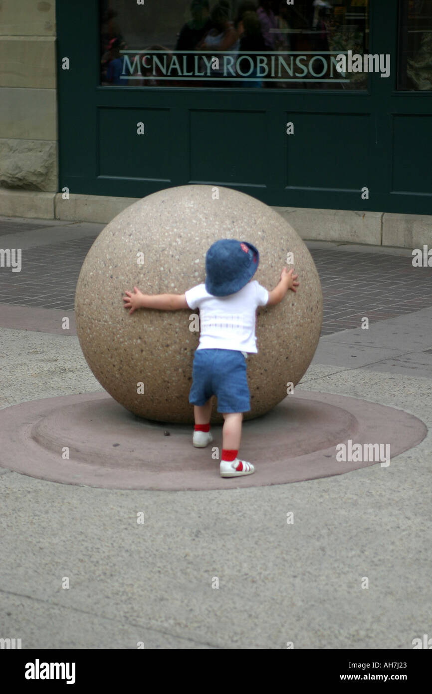 Small boy trying to move stone sculpture 'I can do this ' Stock Photo ...