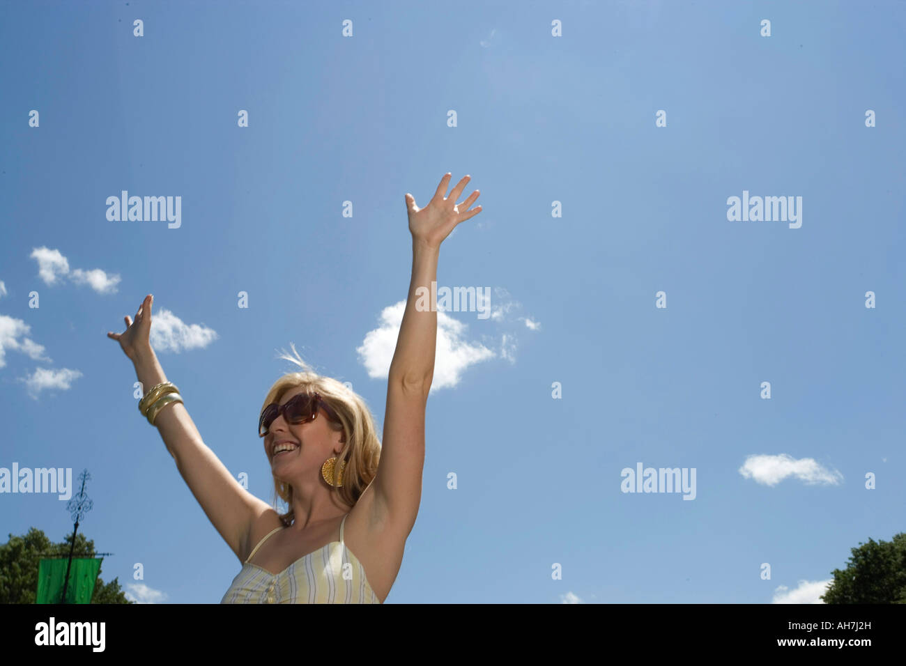 Low angle view of a young woman standing with her arms raised and ...