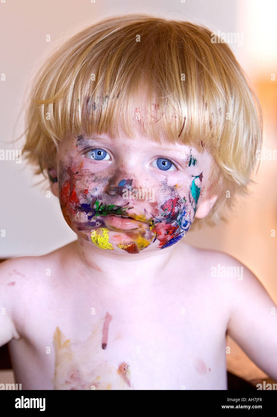 Young boy with face covered in colourful paint Stock Photo - Alamy