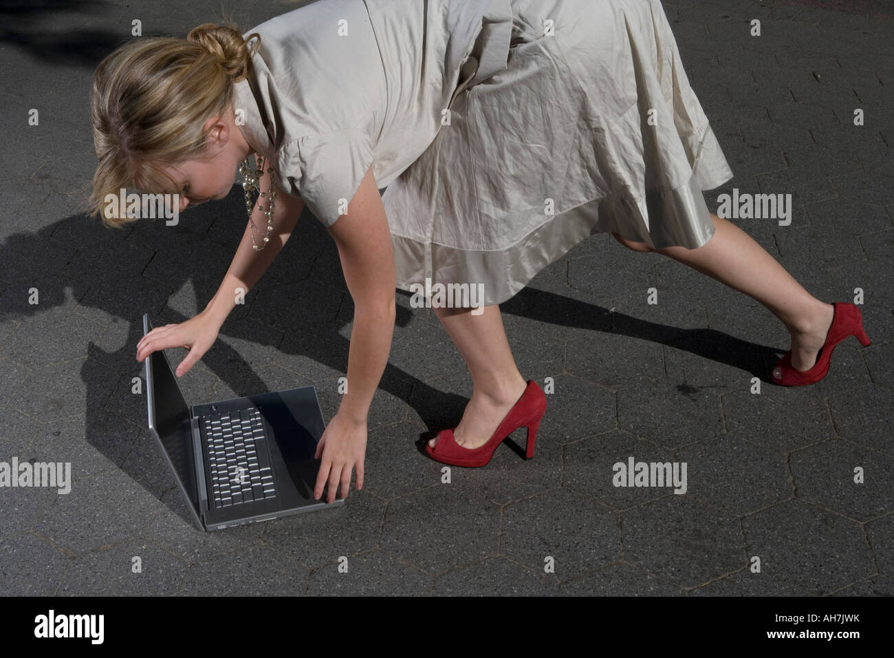 Young woman picking up a laptop from the road Stock Photo - Alamy