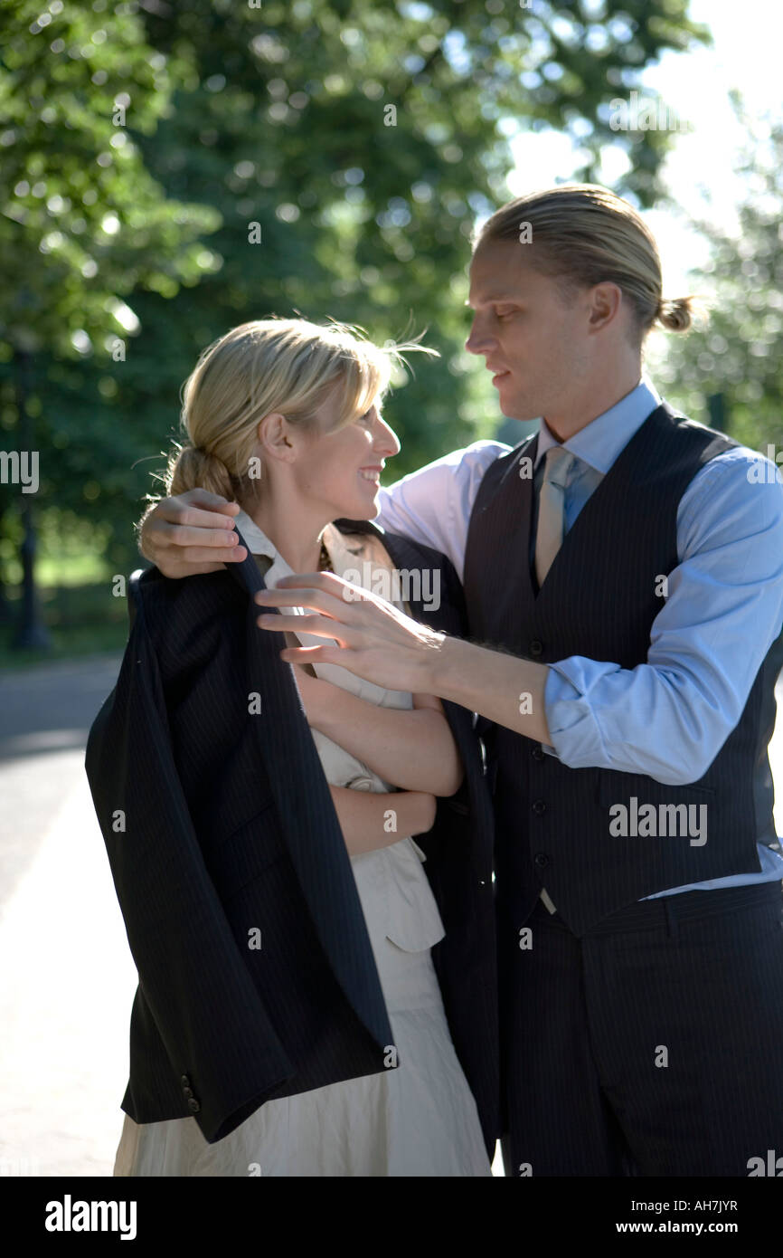 Young man putting his coat around a young woman's shoulders Stock Photo ...