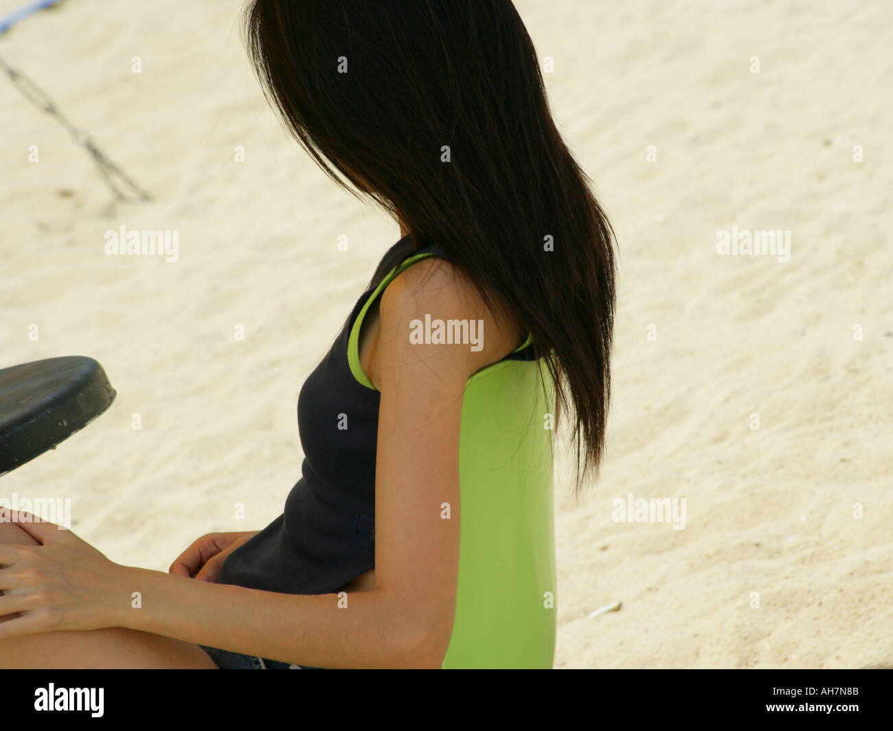 Side profile of a young woman sitting on a chair on the beach Stock ...