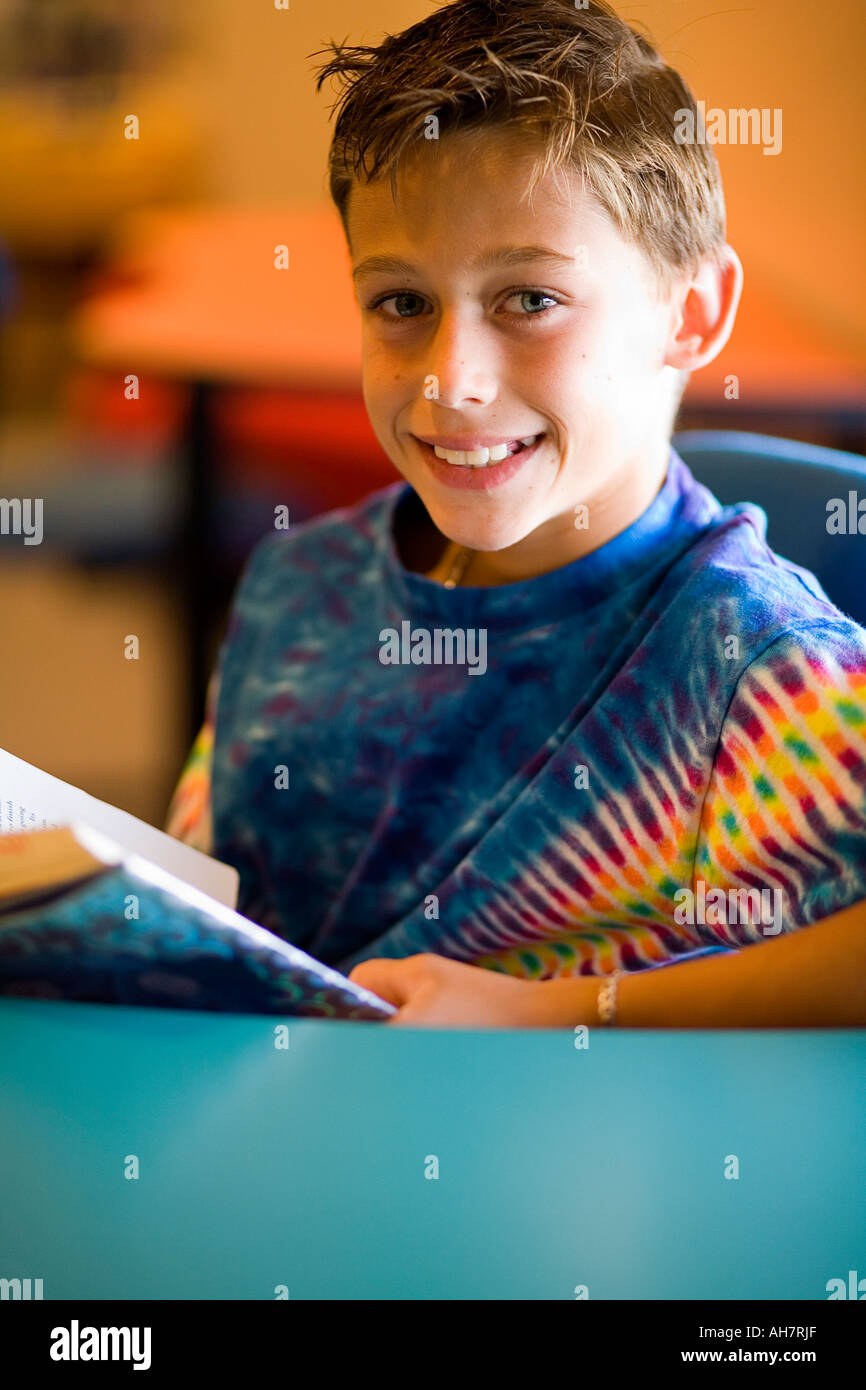 Young boy smiles as he is reading a book in the library Stock Photo - Alamy