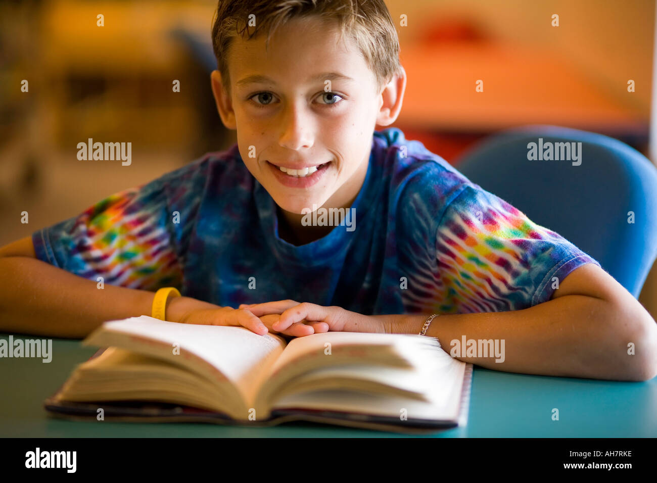 Young boy smiling and looking up from reading a book Stock Photo - Alamy