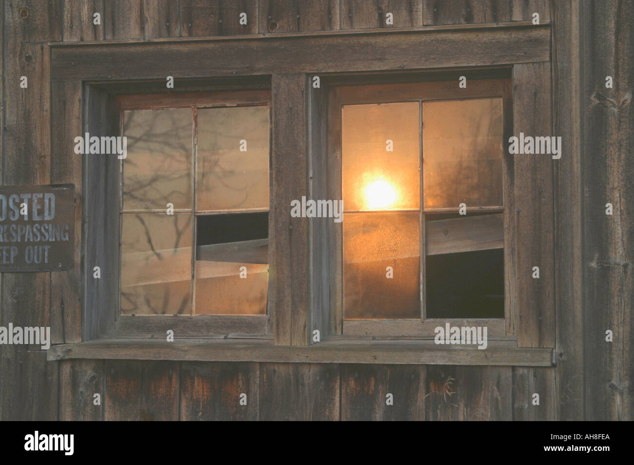 Reflection of the sunrise in the broken window of an abandoned barn ...