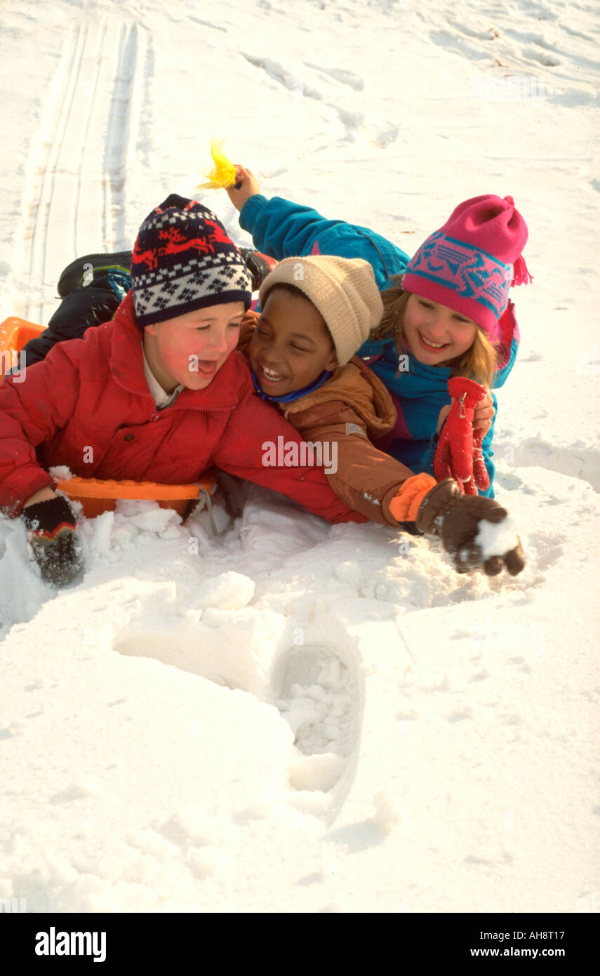 Black and white friends age 7 through 10 falling off snow sled. St Paul ...