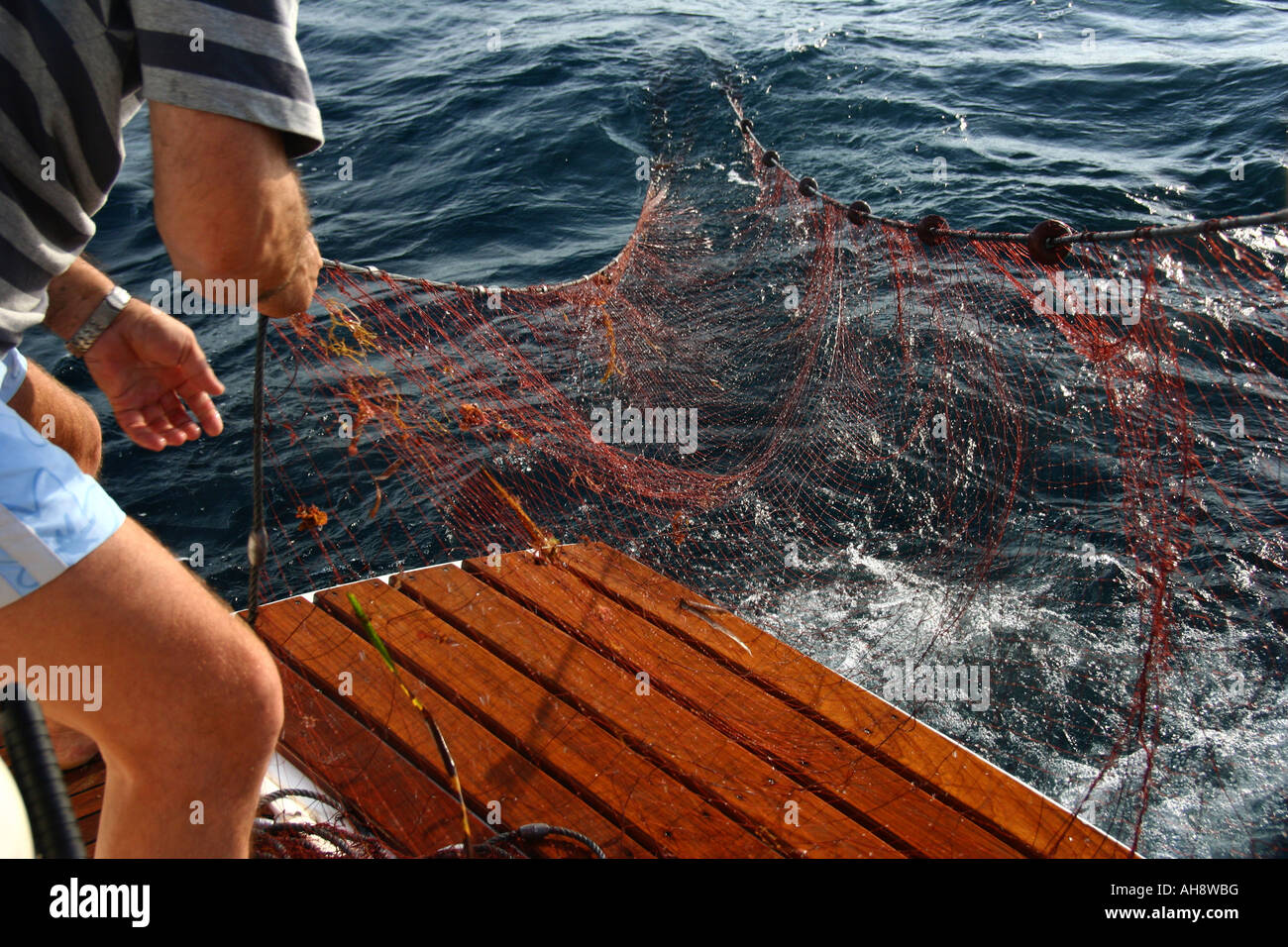 Fisherman pulling a net towards his ship Stock Photo - Alamy