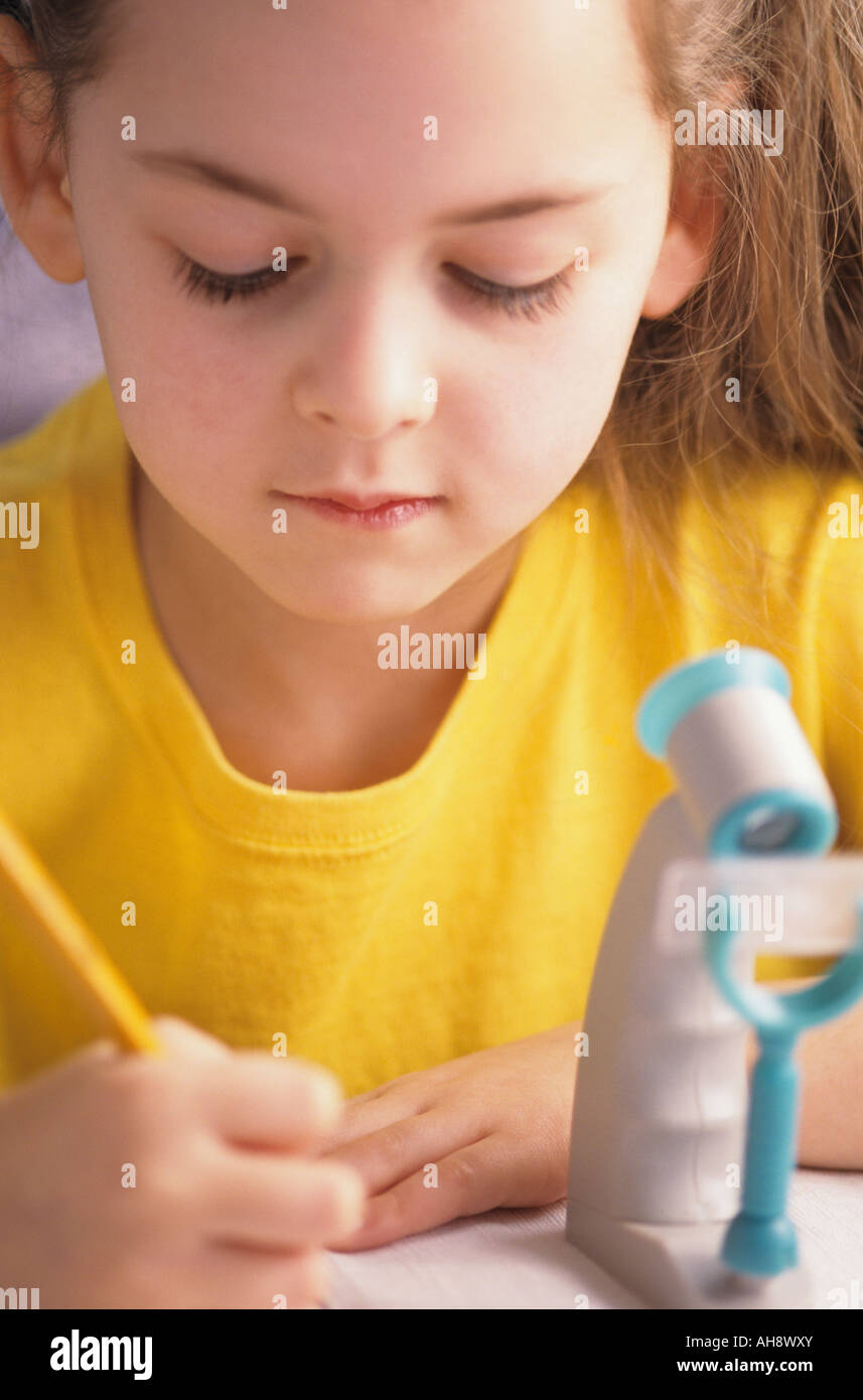Young girl writing home school studying with microscope Stock Photo - Alamy