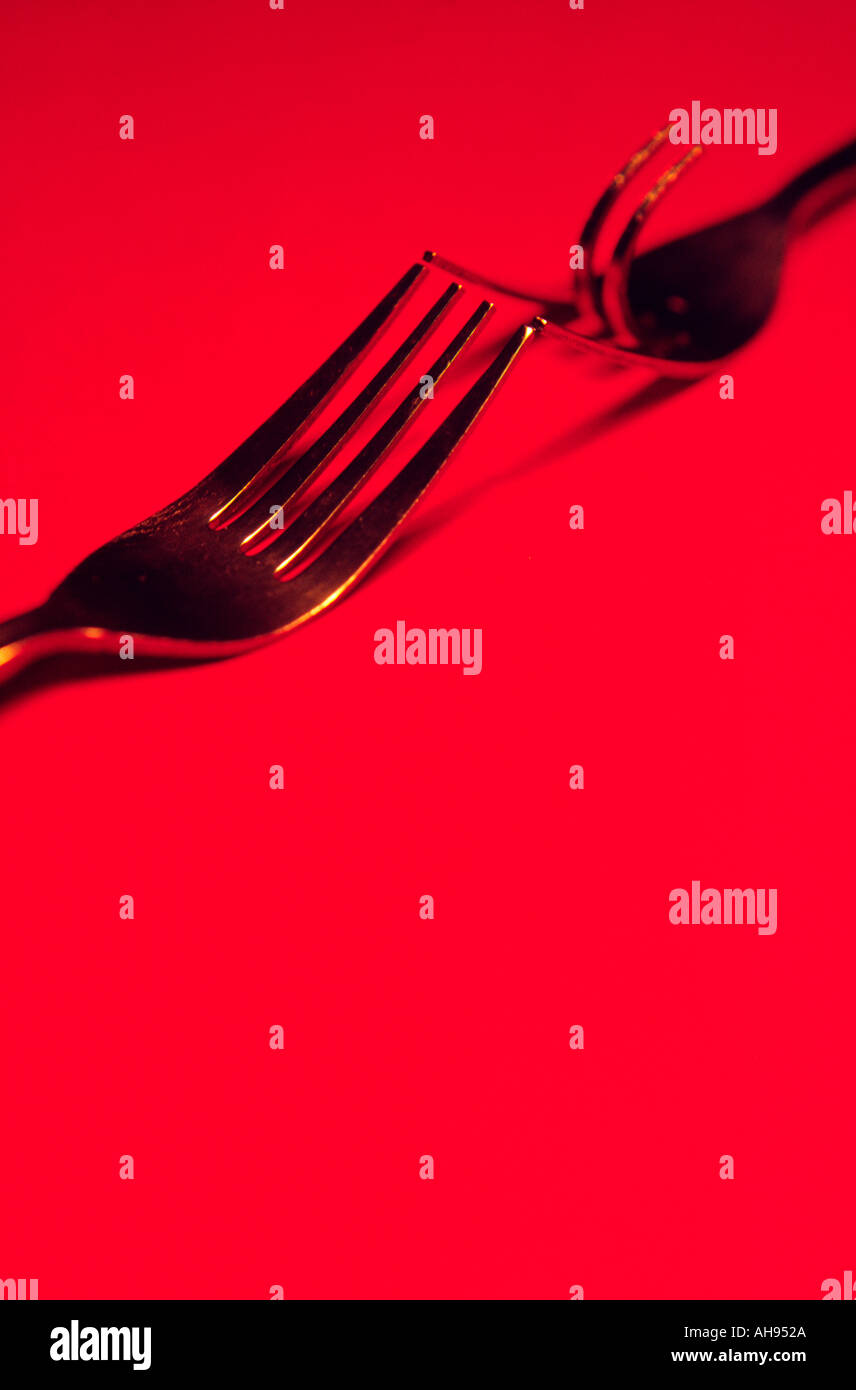 Two forks head to head one has bent prongs backwards on strong red ...