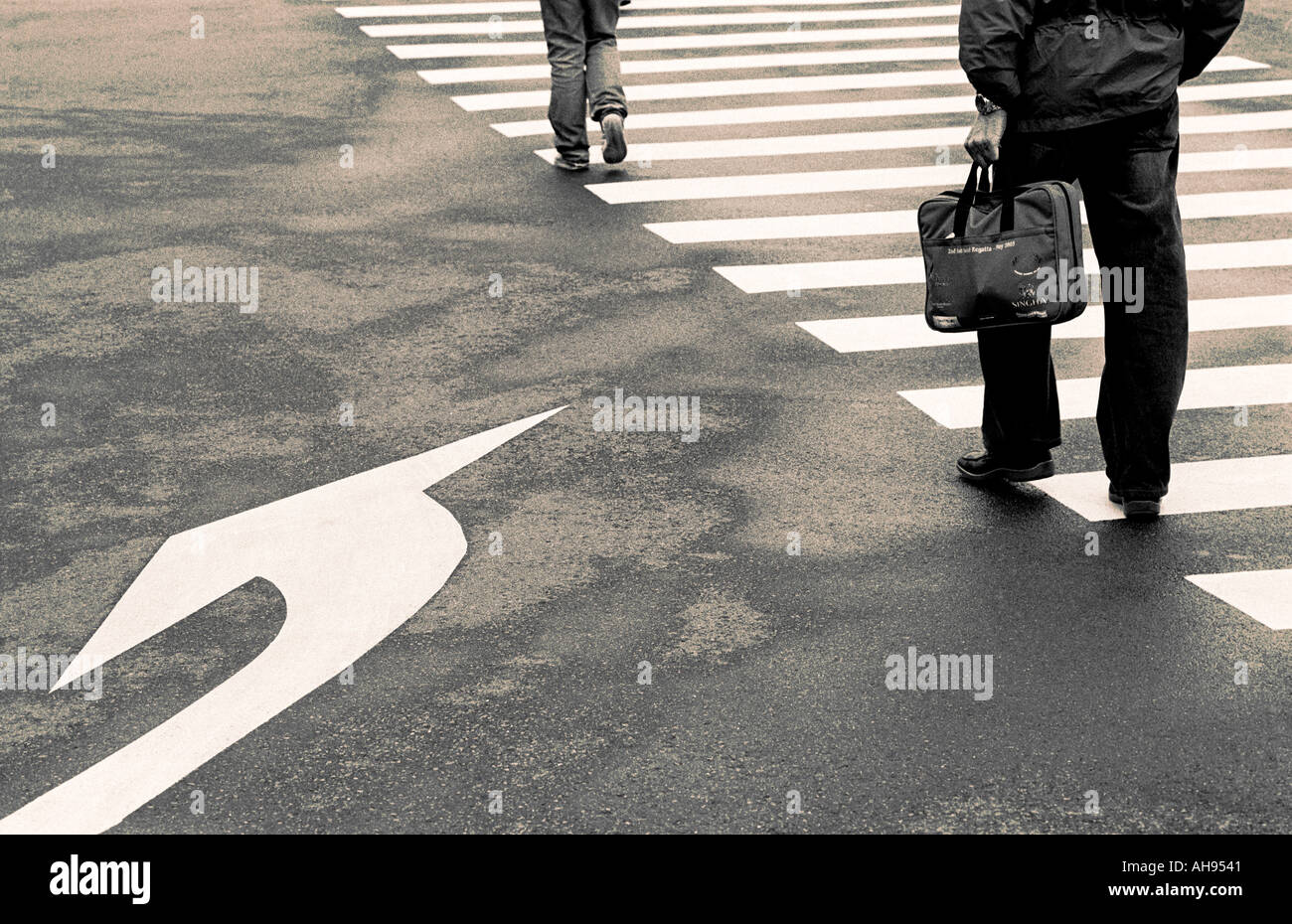 Two male figures cropped at their legs crossing a road with large ...