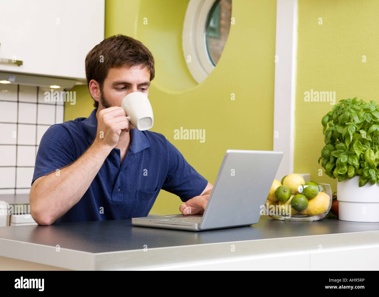 Using a laptop computer in the kitchen while enjoying a warm drink ...