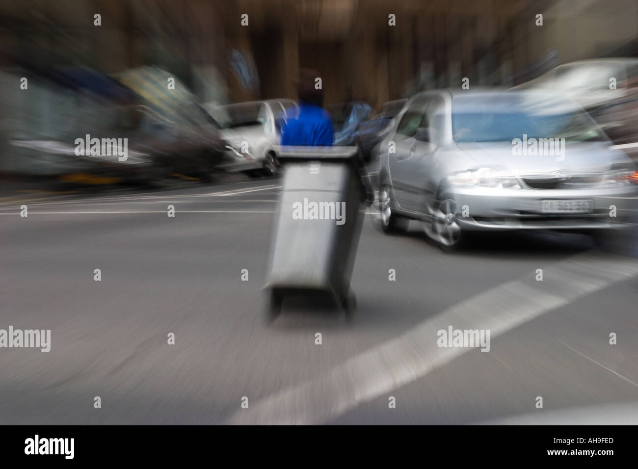Black worker pulling a garbage container over the street Capetown South ...