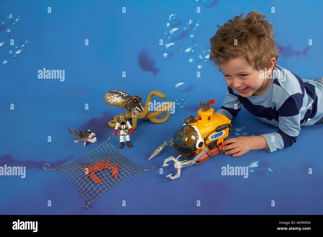 boy playing with deep sea style toys against a sea blue background ...