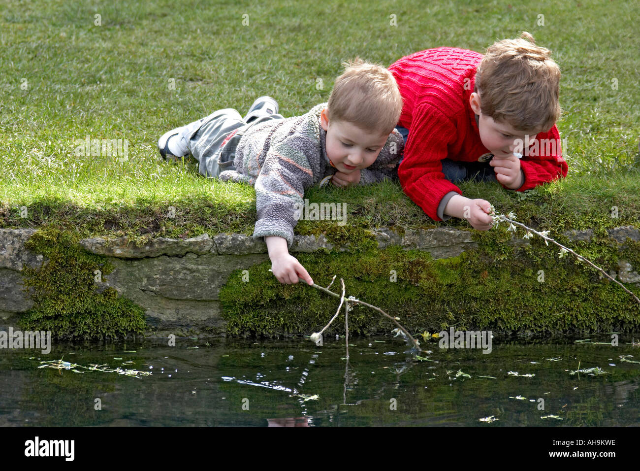 Two young boys playing beside a pond Stock Photo - Alamy