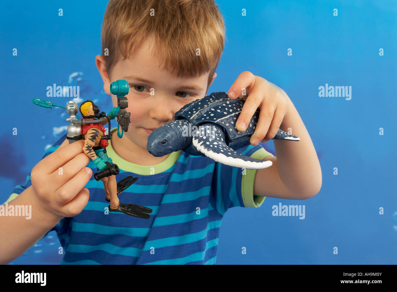 Boy playing with sea turtle and diver against a sea blue background ...