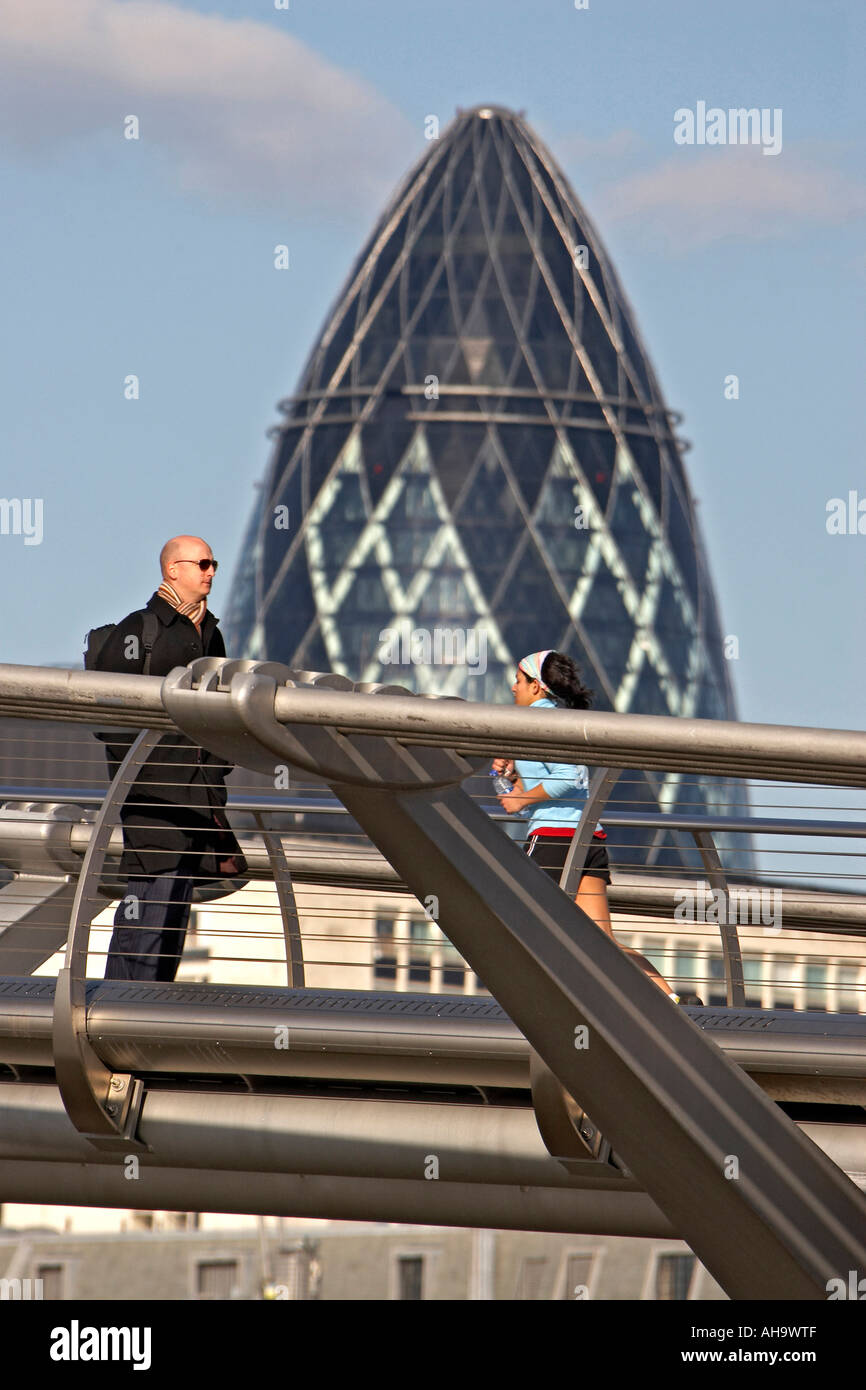 People walking across Millenium Bridge over River Thames with Swiss Re ...