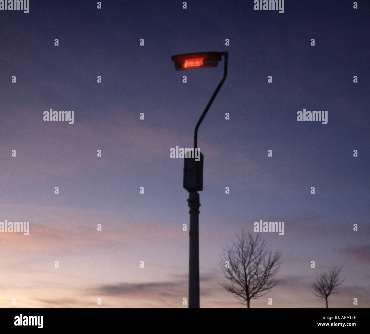 looking up to a lit up lamp post with the sky behind turning into dusk ...