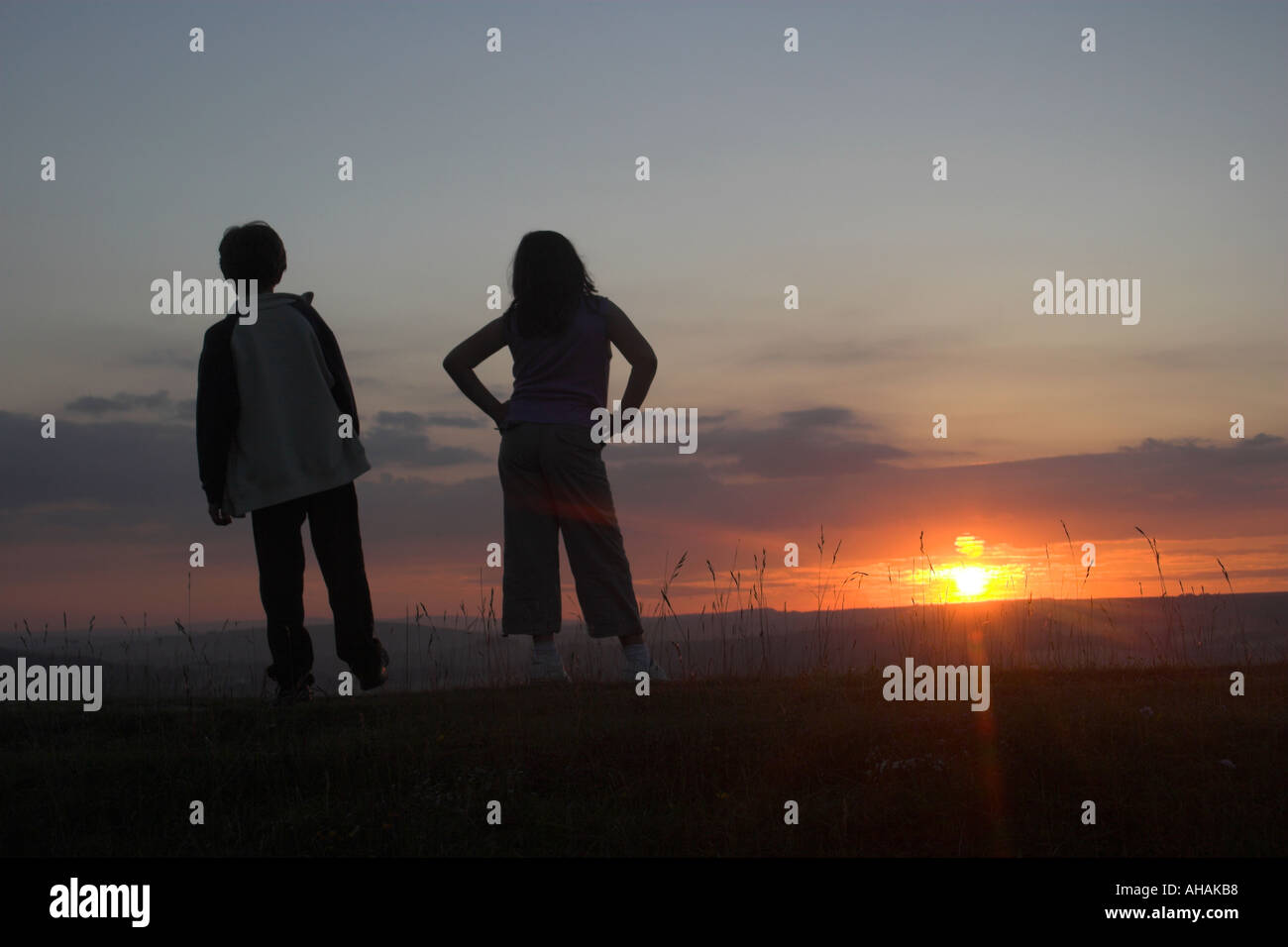 10 year old boy and girl standing together watching the sun set (or ...