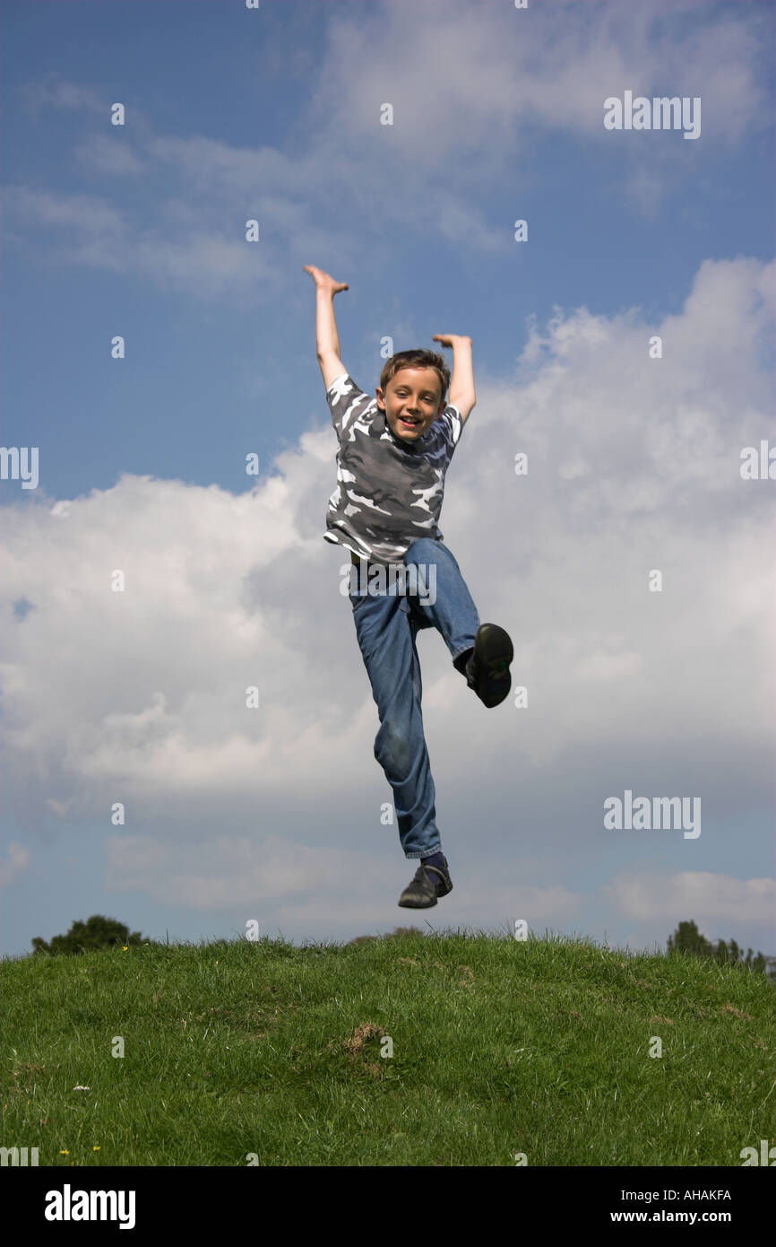 10 year old boy jumping arms stretched out behind Stock Photo - Alamy