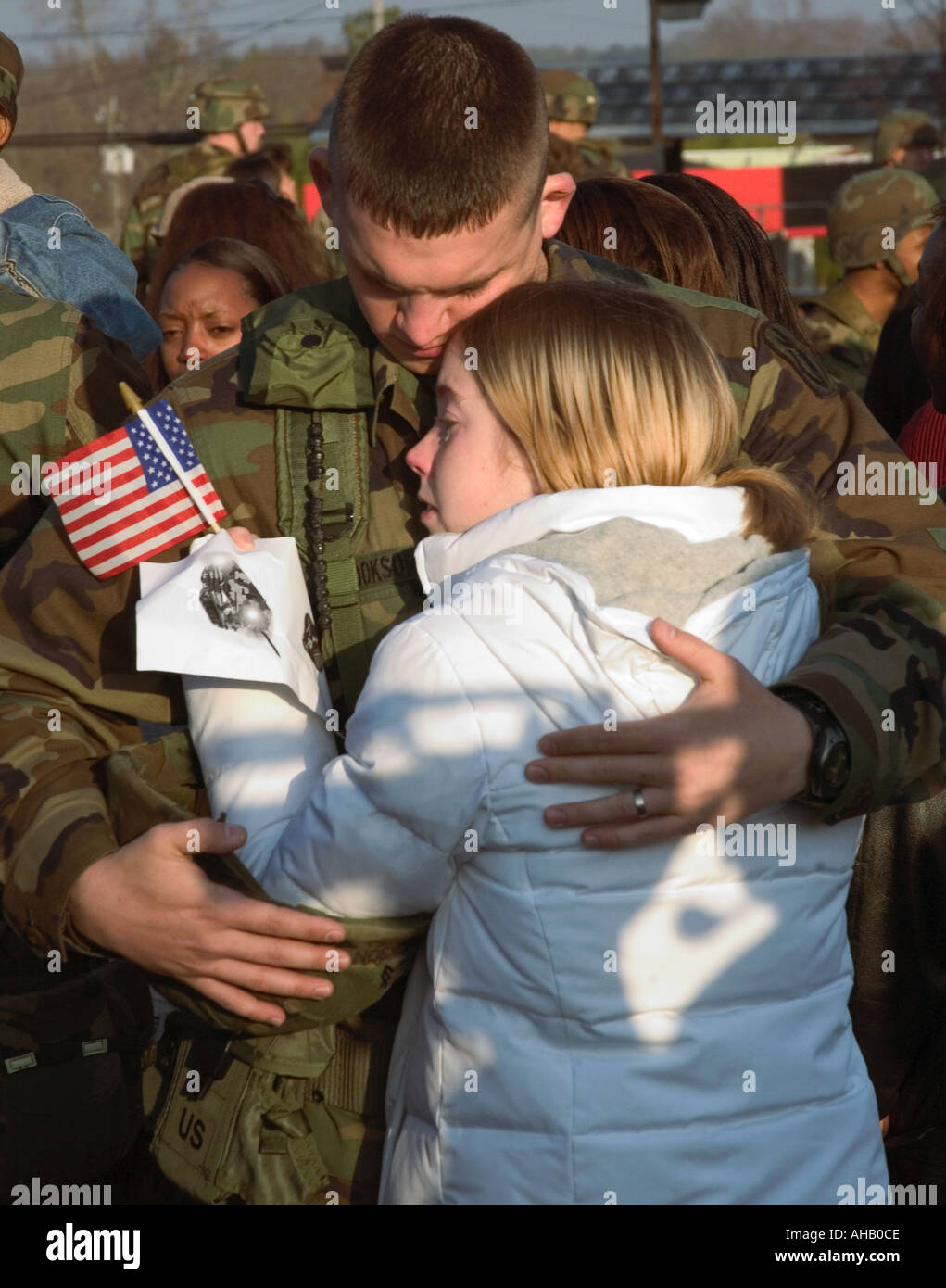 Caucasian National Guard soldier hugs his wife who is holding a U.S ...