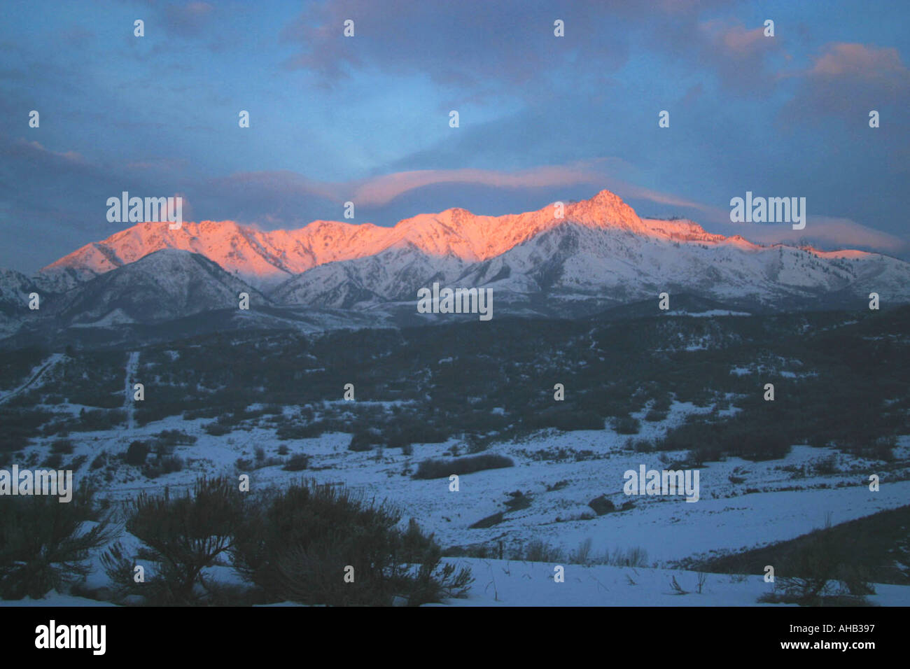 Early morning sunlight changes snow capped mountains to a flaming ...