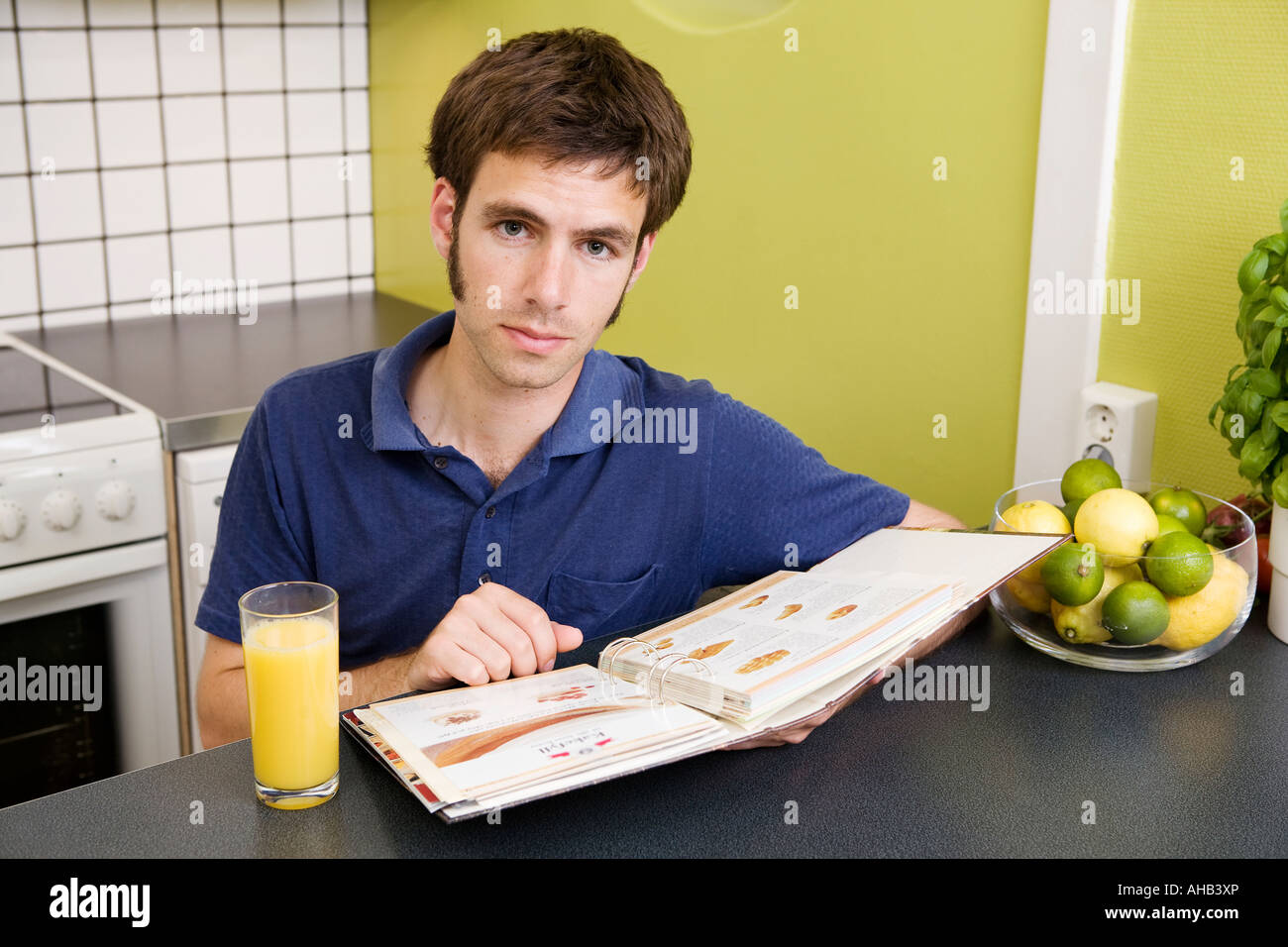 A young man in the kitchen looking at recipes Stock Photo - Alamy