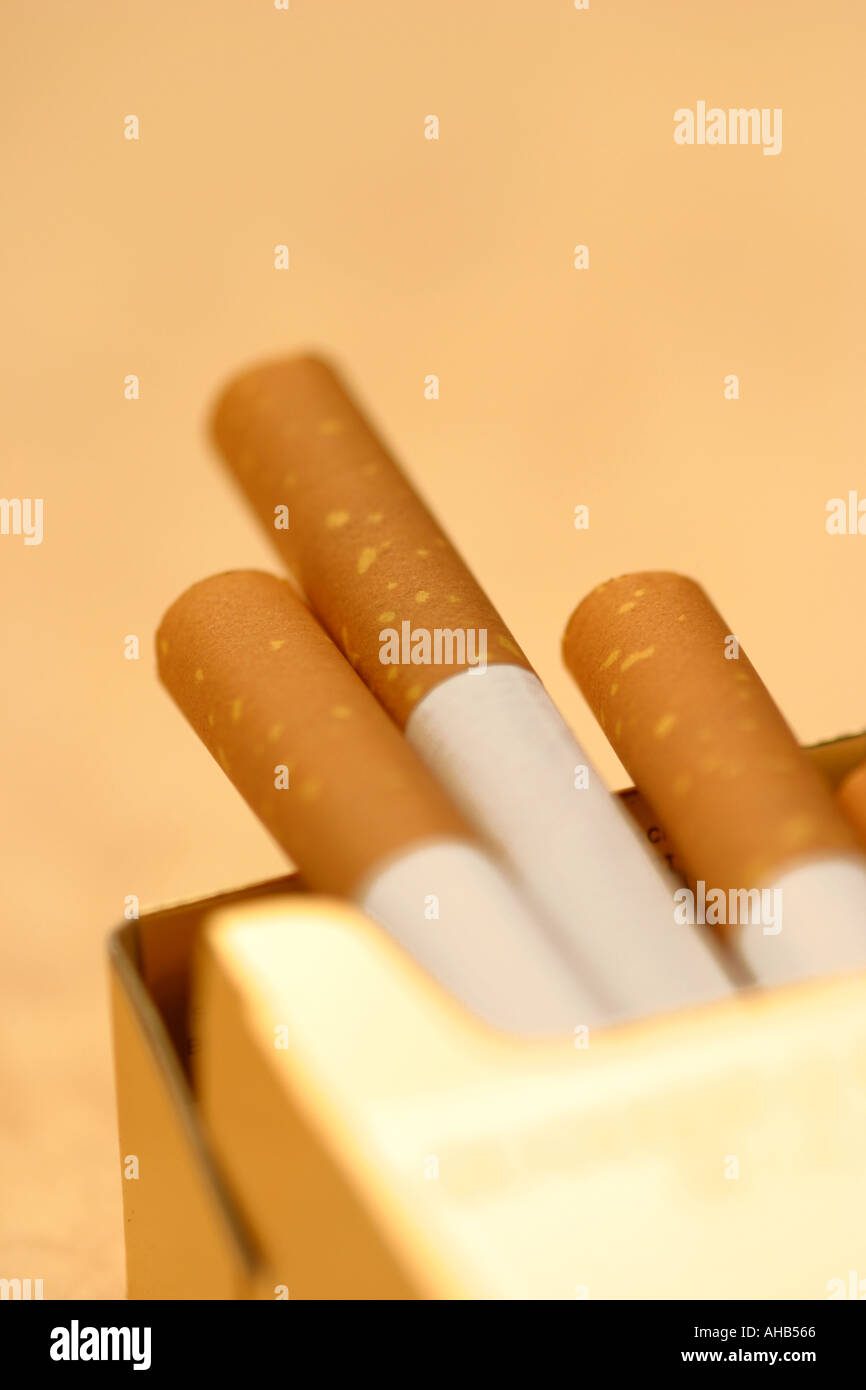Three cigarettes in a packet on a yellow background Stock Photo - Alamy