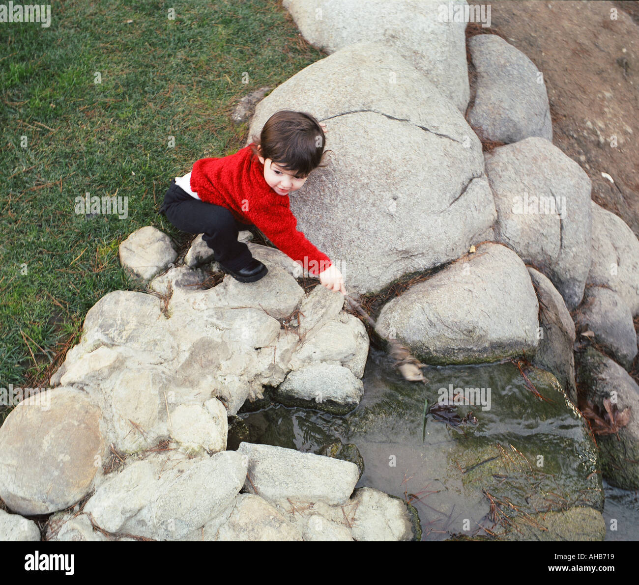 Child playing with tree branch in a stream Stock Photo - Alamy
