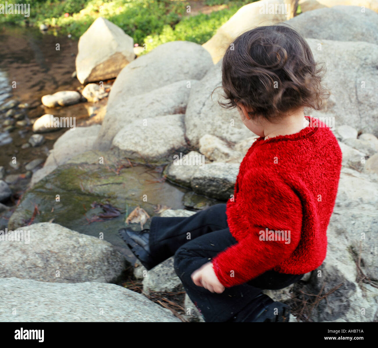 Child playing with tree branch in a stream Stock Photo - Alamy