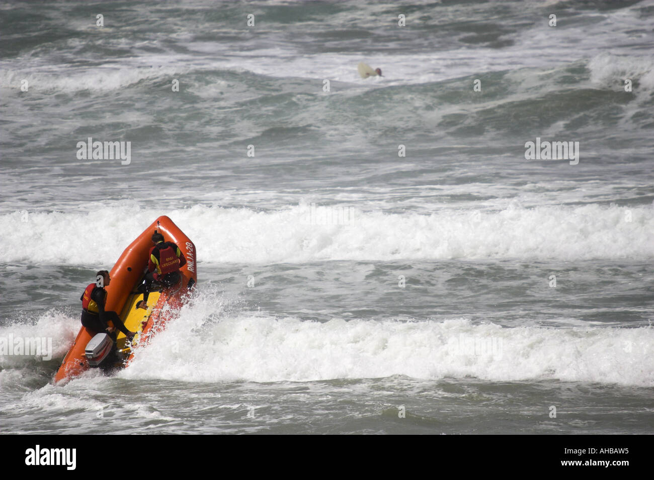Two beach lifeguards head out through the surf in their life boat ...
