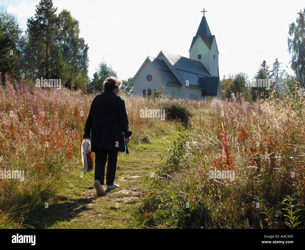 Woman walking to church late summerevening Stock Photo - Alamy