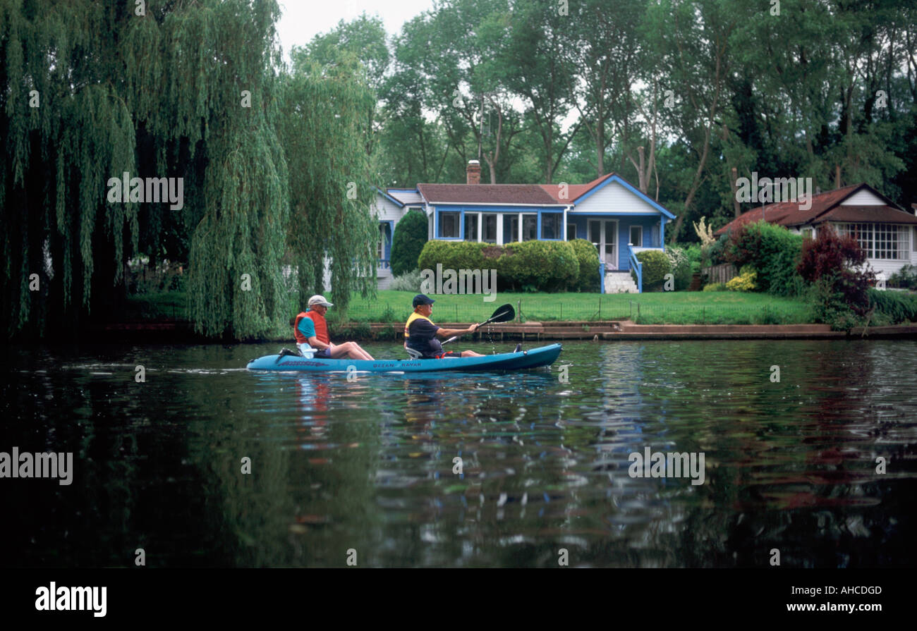 Two men paddling a kayak on the River Thames, passing riverside ...