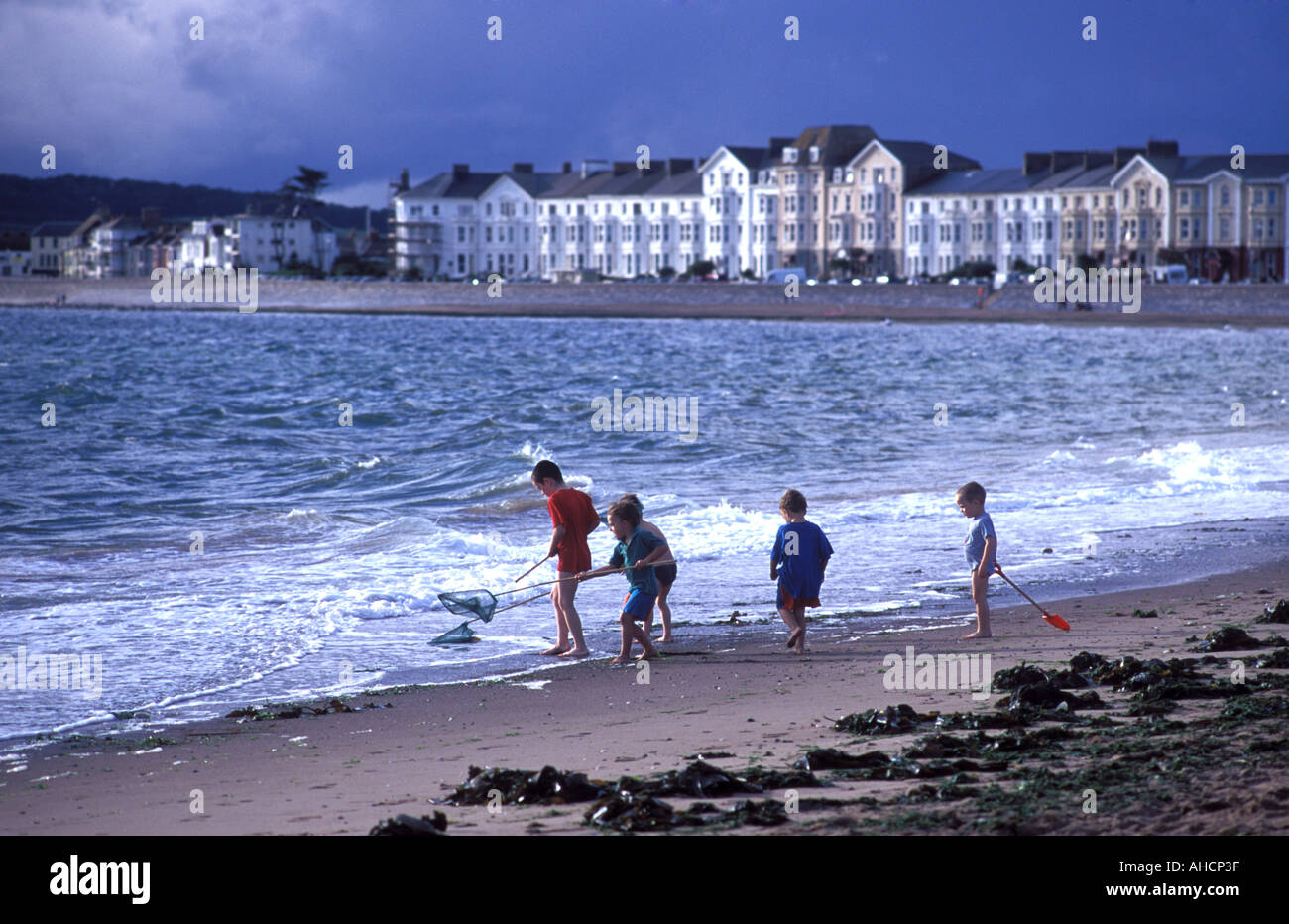 Children fishing and playing in stormy summer weather at Exmouth Devon ...