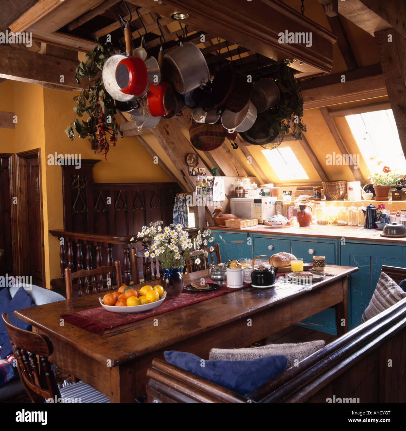 Pans on metal rack above rectangular wooden table and bench in yellow ...