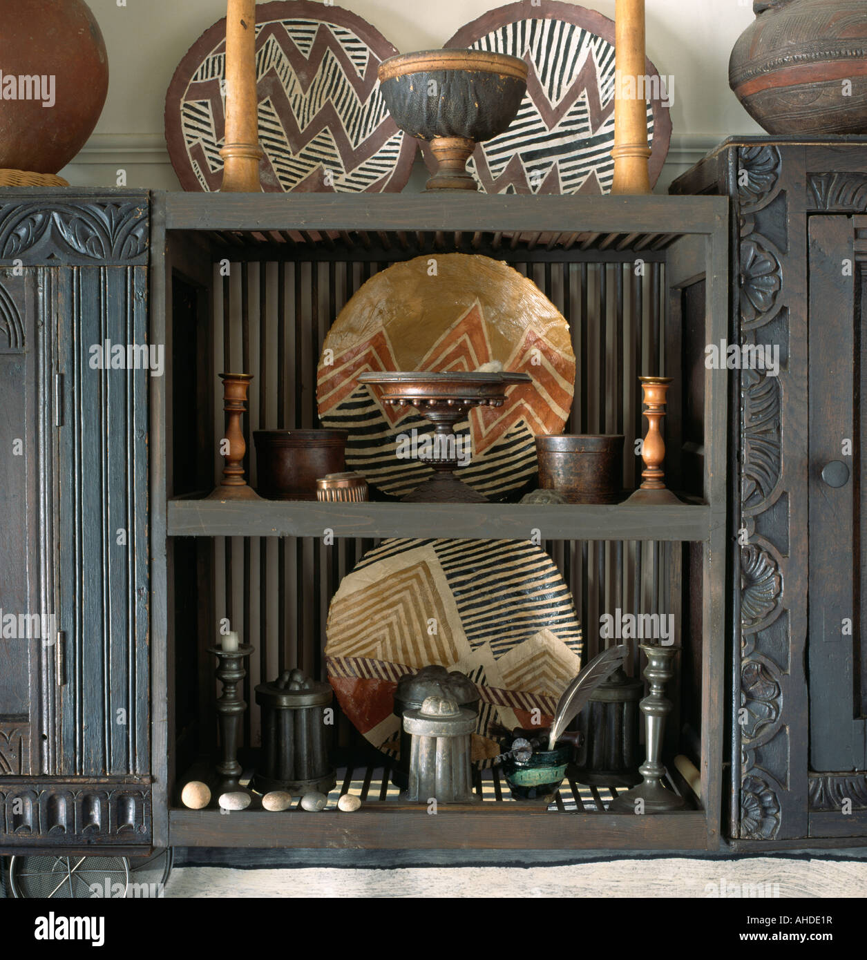 Collection of African pottery and artefacts on carved wooden shelves ...