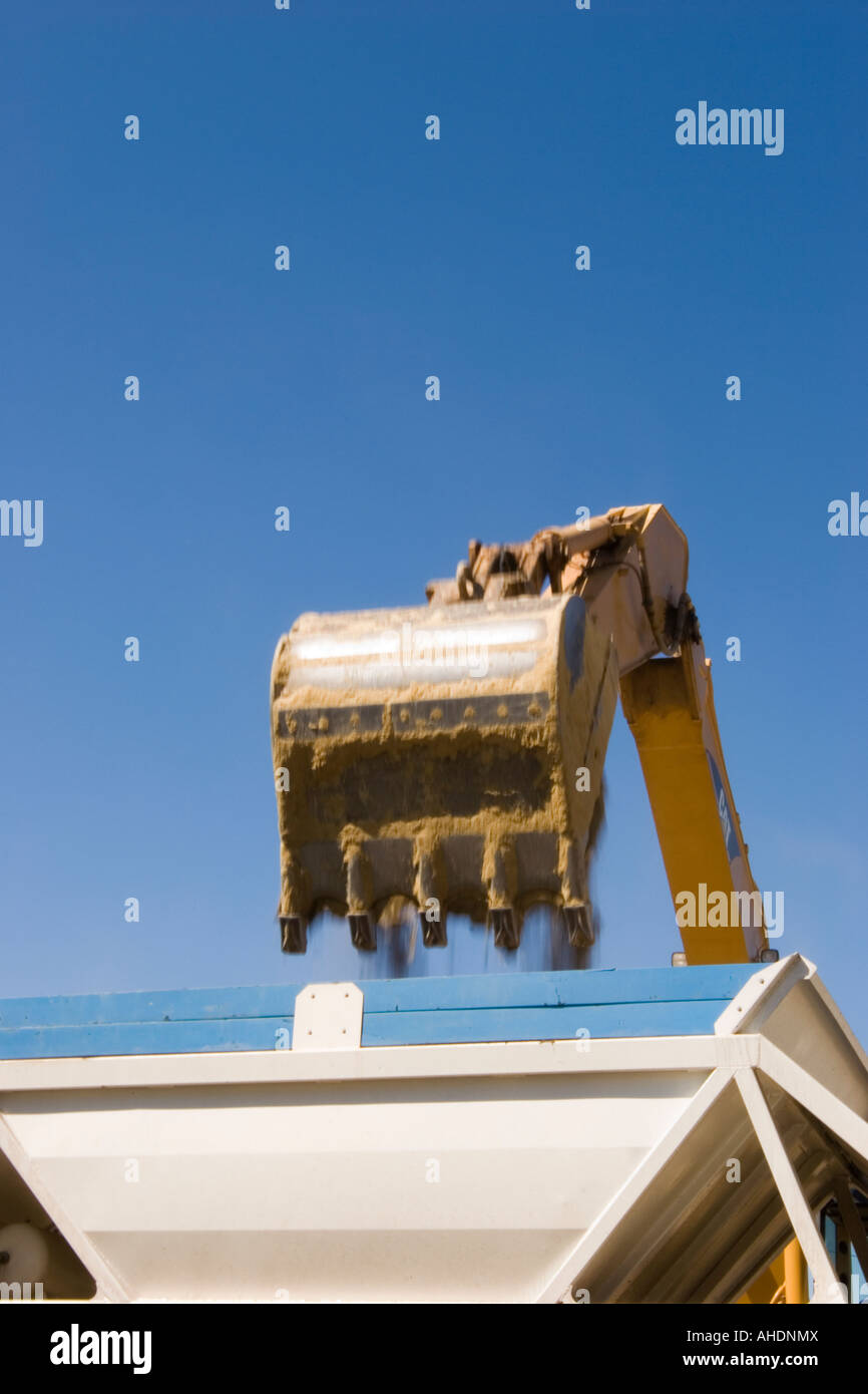 A backhoe drops gravel into a waiting dump truck Stock Photo - Alamy