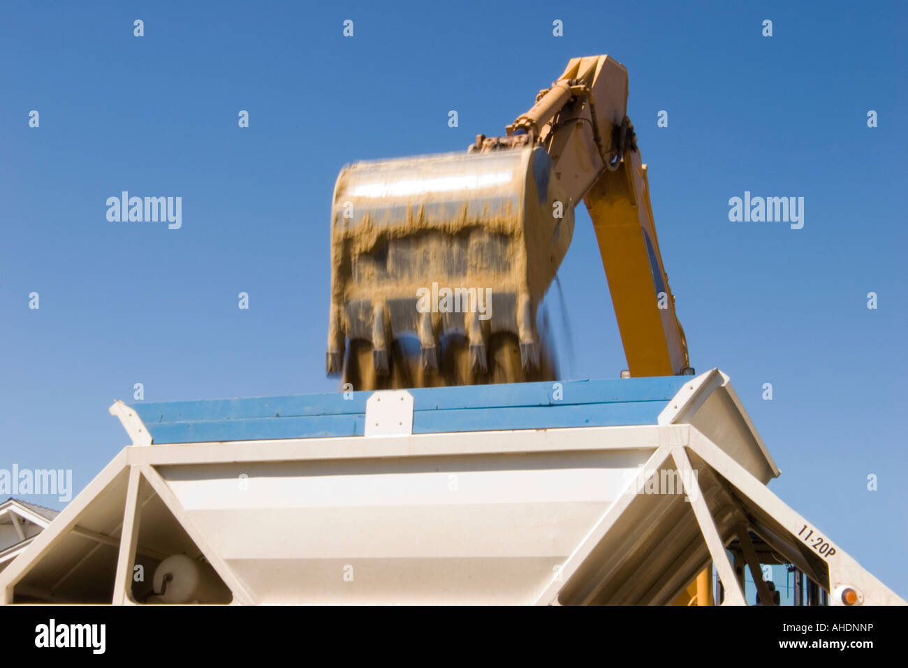 A backhoe drops gravel into a waiting dump truck Stock Photo - Alamy