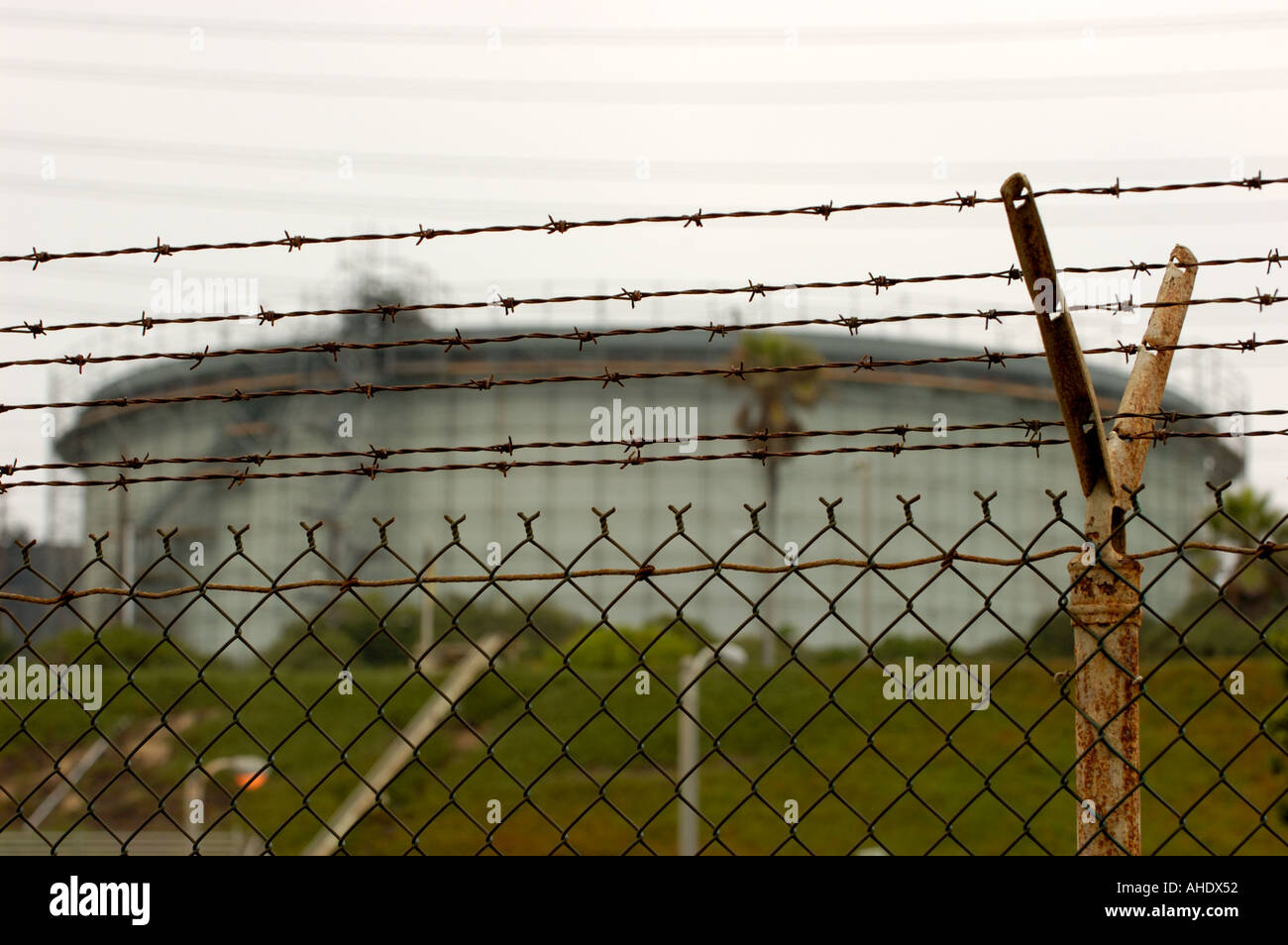 Chemical tanks behind barbed wire Stock Photo - Alamy