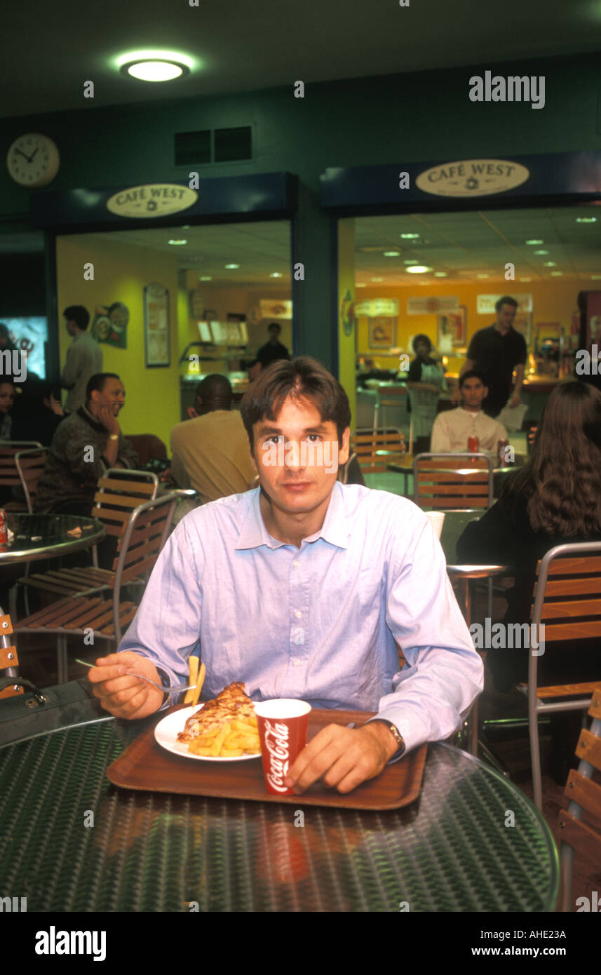 Young man eating fast food in cafe Stock Photo - Alamy