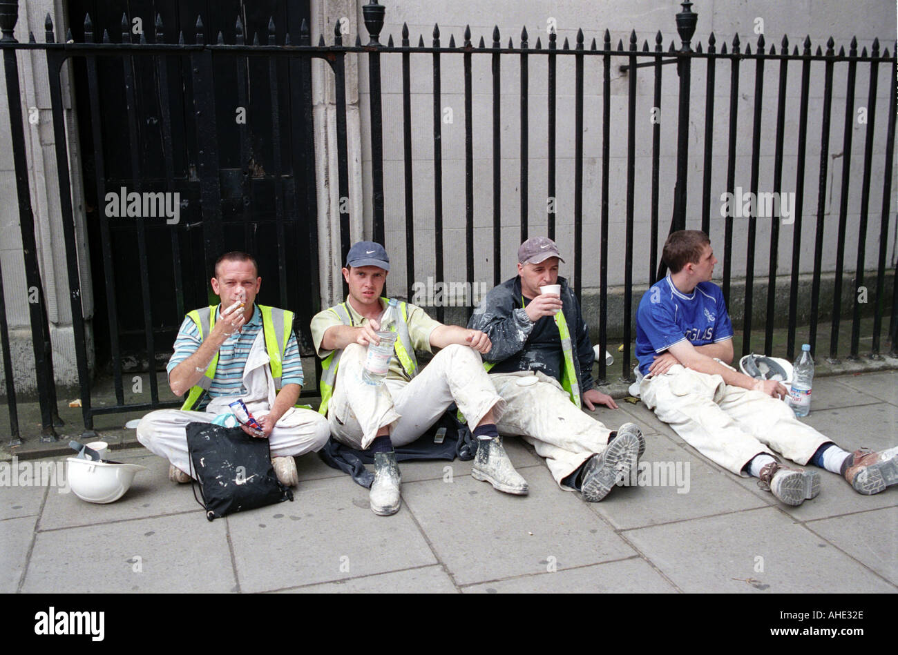 Group of workmen taking lunch break from work on pavement in central ...