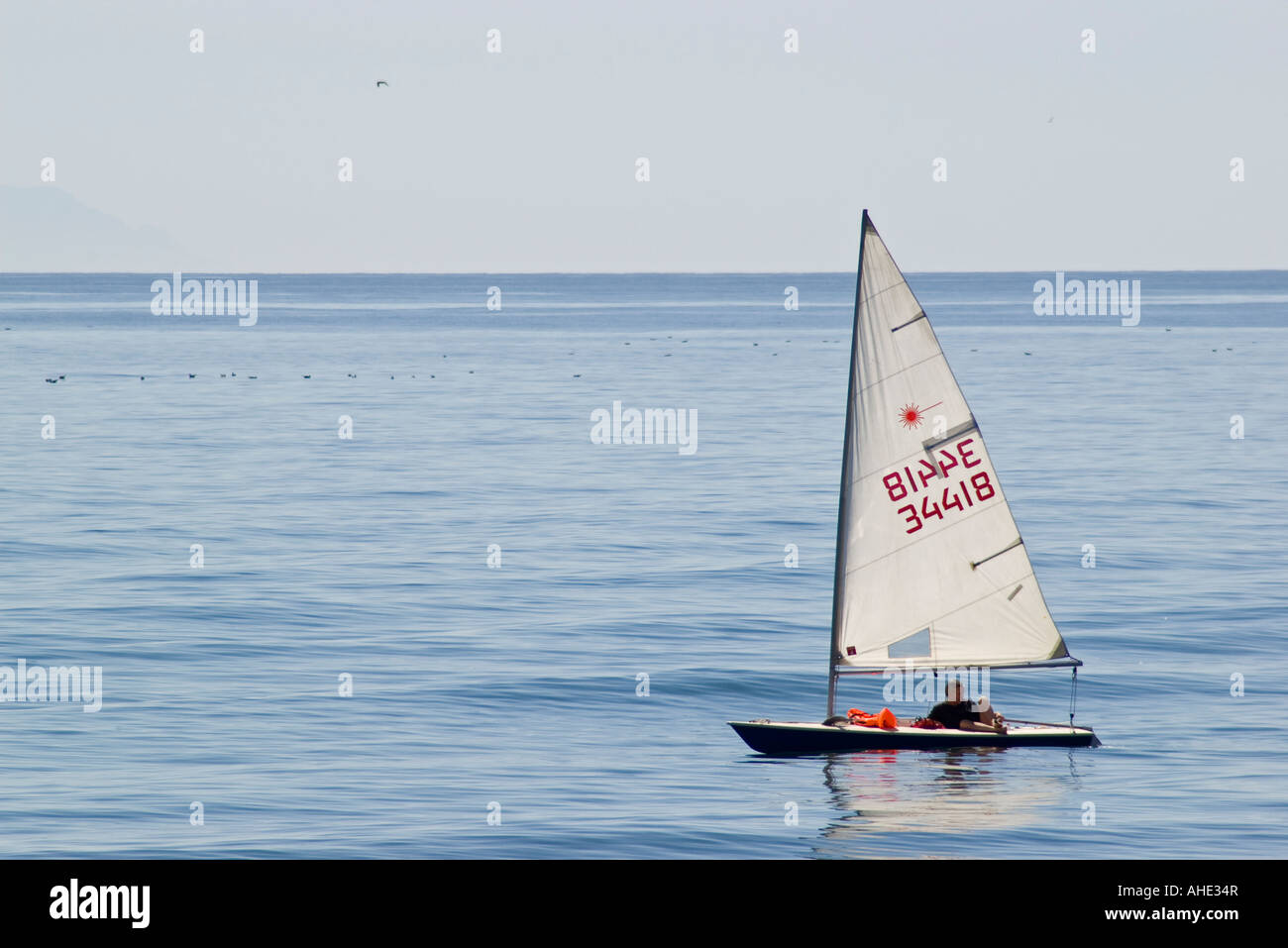 Small sailing dinghy becalmed in light breezes Stock Photo - Alamy