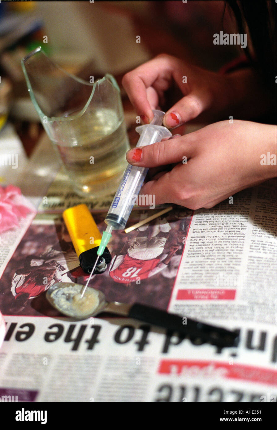 Preparing to inject heroin by filling syringe with heated powder Stock ...