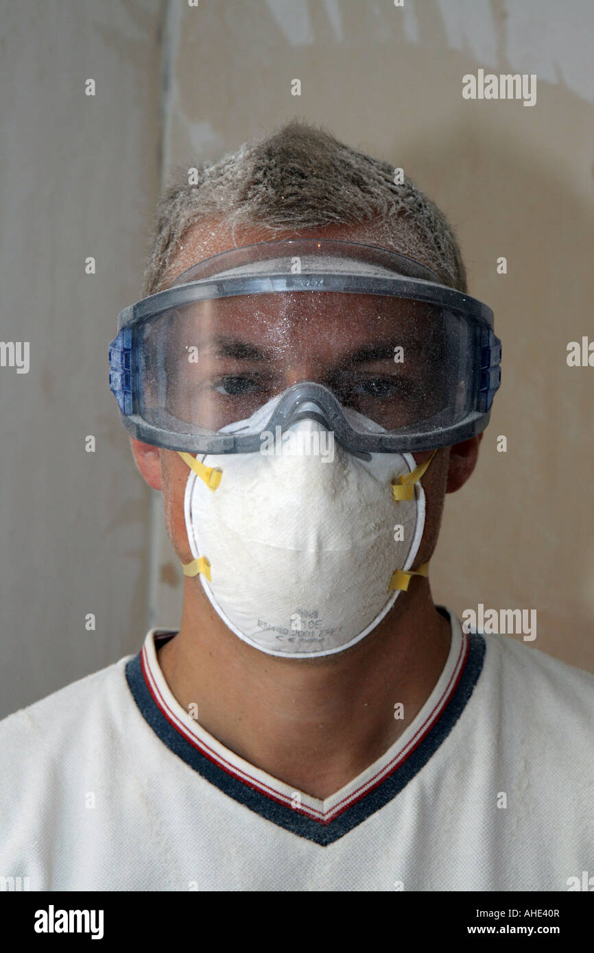 Dusty man after sandpapering a wall before putting up new wallpaper He ...