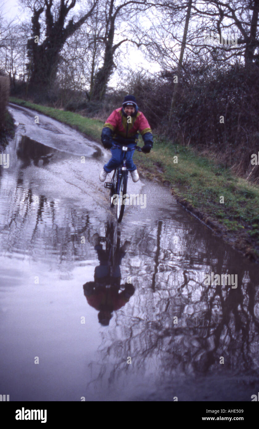Woman rides bike through large puddle Mettingham Norfolk Stock Photo ...