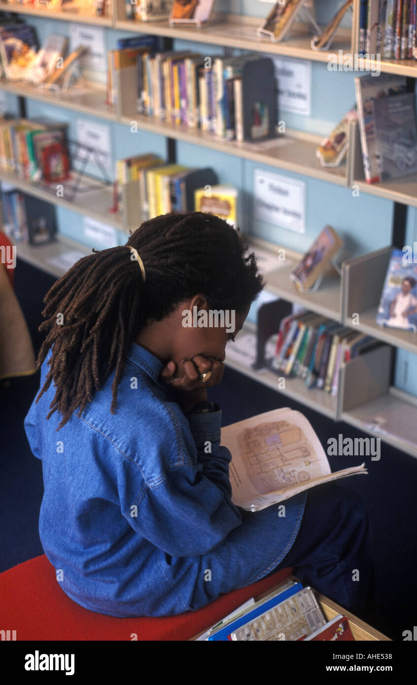 A young boy reading a book in the library of a primary school, Clapton ...